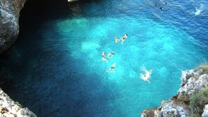 Piscina azul e límpida rodeada por penhascos rochosos.