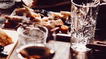 Uma mesa com queijos variados, uma taça de vinho e um copo de água.