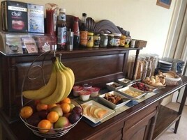 Um buffet de café da manhã com diversas frutas, doces e bebidas.