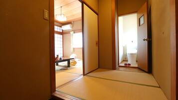 Um quarto japonês tradicional com piso de tatame, porta deslizante e uma bacia.