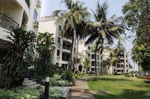 Um hotel com vários andares e varandas, rodeado por vegetação exuberante e palmeiras.
