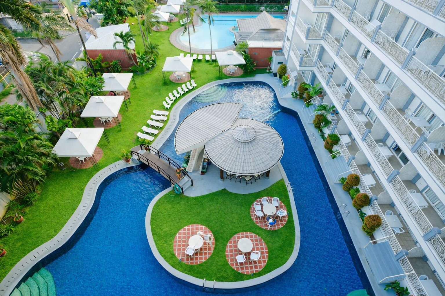 Um hotel com piscina, áreas de estar ao ar livre e uma ponte que liga diferentes partes da propriedade.
