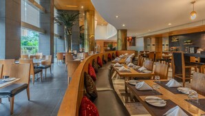 Um restaurante moderno com área de estar curvada, mesas e cadeiras de madeira.