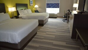 Quarto de hotel com duas camas, uma escrivaninha, uma cadeira, uma televisão e uma janela com vista.