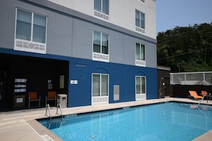 Um edifício moderno com piscina, área de estar externa e espaço coberto com cadeiras.