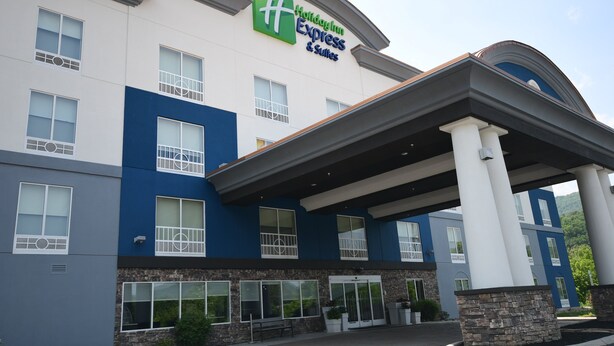 Um hotel Holiday Inn Express & Suites com fachada moderna, grandes janelas e entrada coberta.