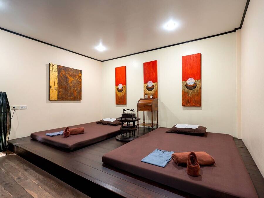 Um quarto com duas macas de massagem, uma mesa pequena e uma cadeira.