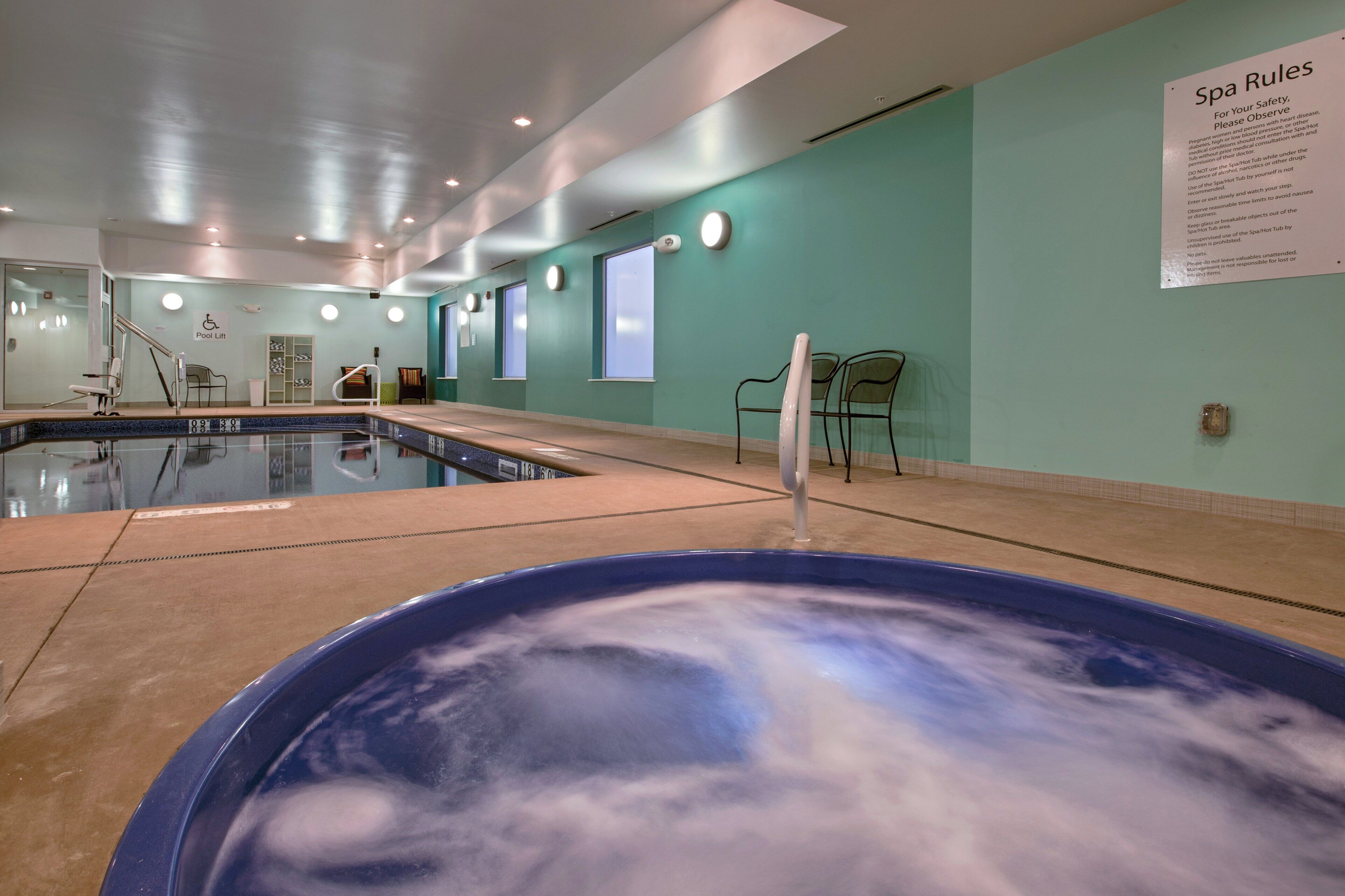 Área de spa com banheira de hidromassagem, piscina e espreguiçadeiras.