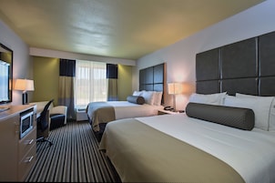 Quarto de hotel com duas camas, uma escrivaninha e uma cadeira.