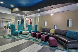 Um lobby moderno com áreas de estar, carpete estampado e luminárias contemporâneas.