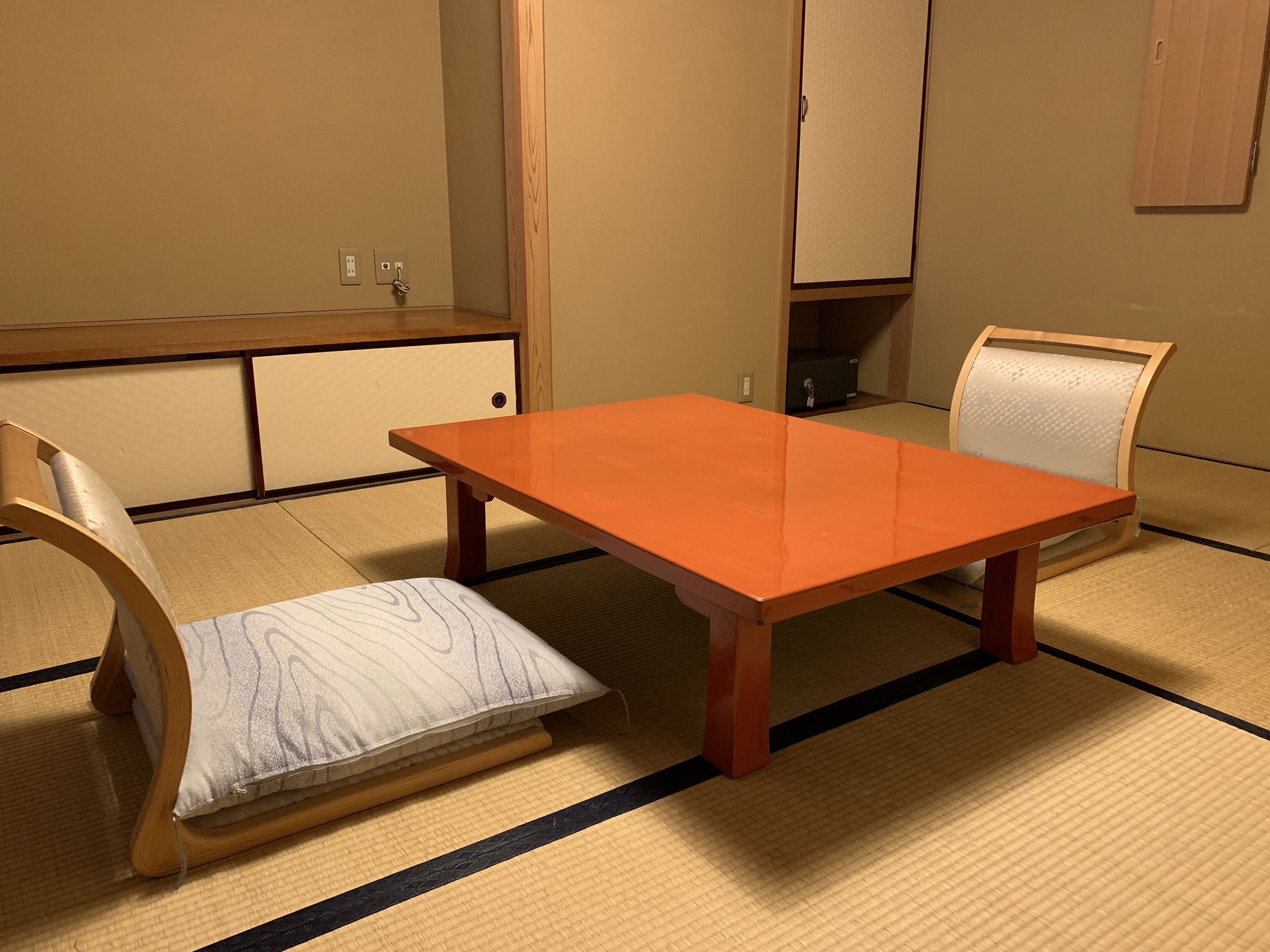 Um quarto tradicional japonês com tatames, uma mesa de madeira e dois tatames com almofadas.