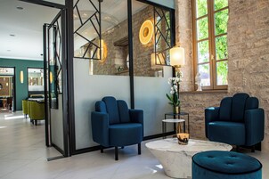 Um interior moderno com dois poltronas azuis, uma mesa de centro de mármore e uma parede de pedra.