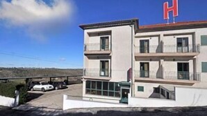Um hotel com vários andares e um grande letreiro em formato de 'H' no telhado, identificando-o como hotel.