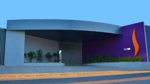 Um edifício moderno com fachada curva, uma parede de destaque roxa e um grande logotipo laranja.