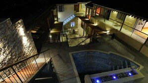 Área externa com vários níveis, piscina, escadas e um muro de pedra.