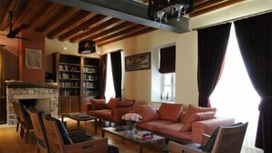 Uma sala de estar acolhedora com lareira, um conjunto de sofás e uma estante de livros.