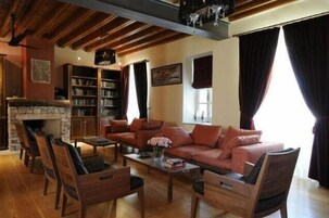 Uma sala de estar acolhedora com lareira, um conjunto de sofás e uma estante de livros.