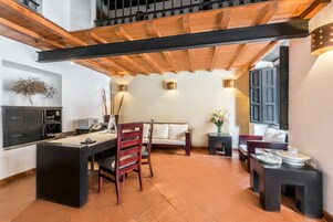 Cozinha espaçosa com teto de madeira, área de refeições com sofá e cadeiras, e uma pequena mesa com pratos.
