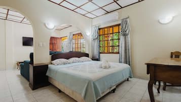Quarto com cama, escrivaninha e janela com cortinas.