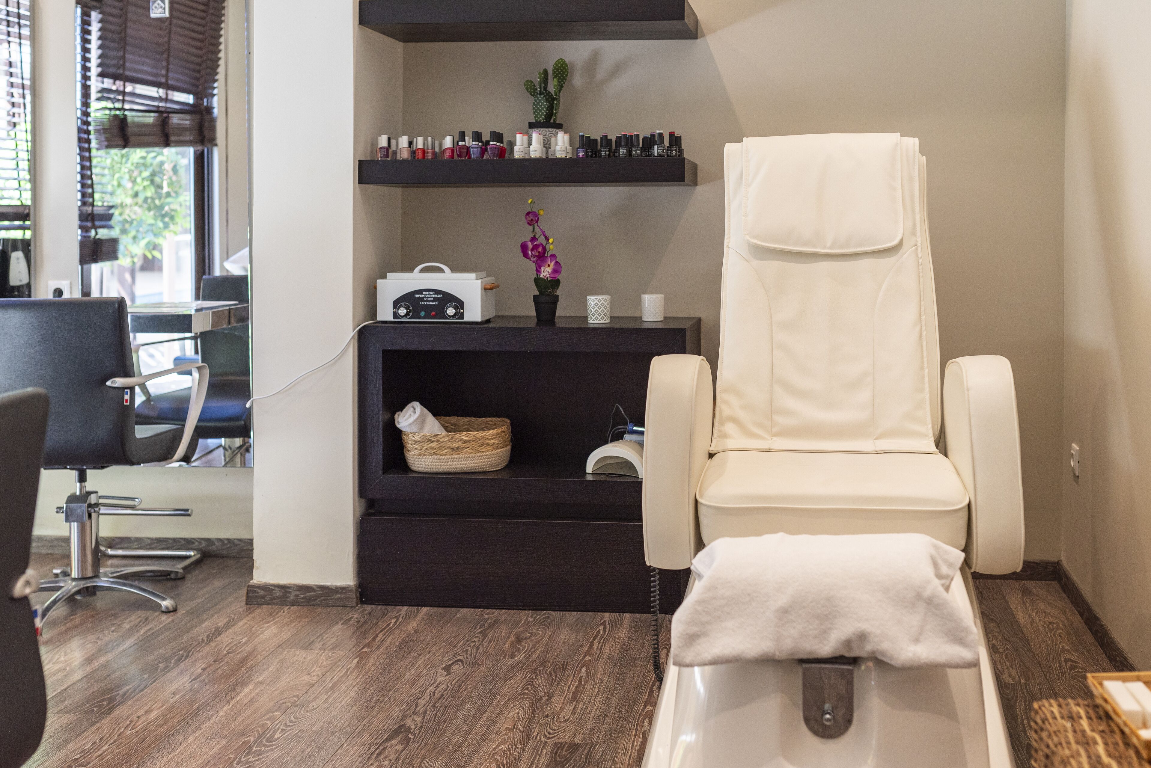 Uma cadeira de massagem, uma estante com diversos objetos e uma cadeira num quarto com soalho de madeira.