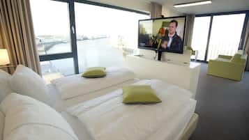 Quarto de hotel com uma cama, televisão e vista para a água.