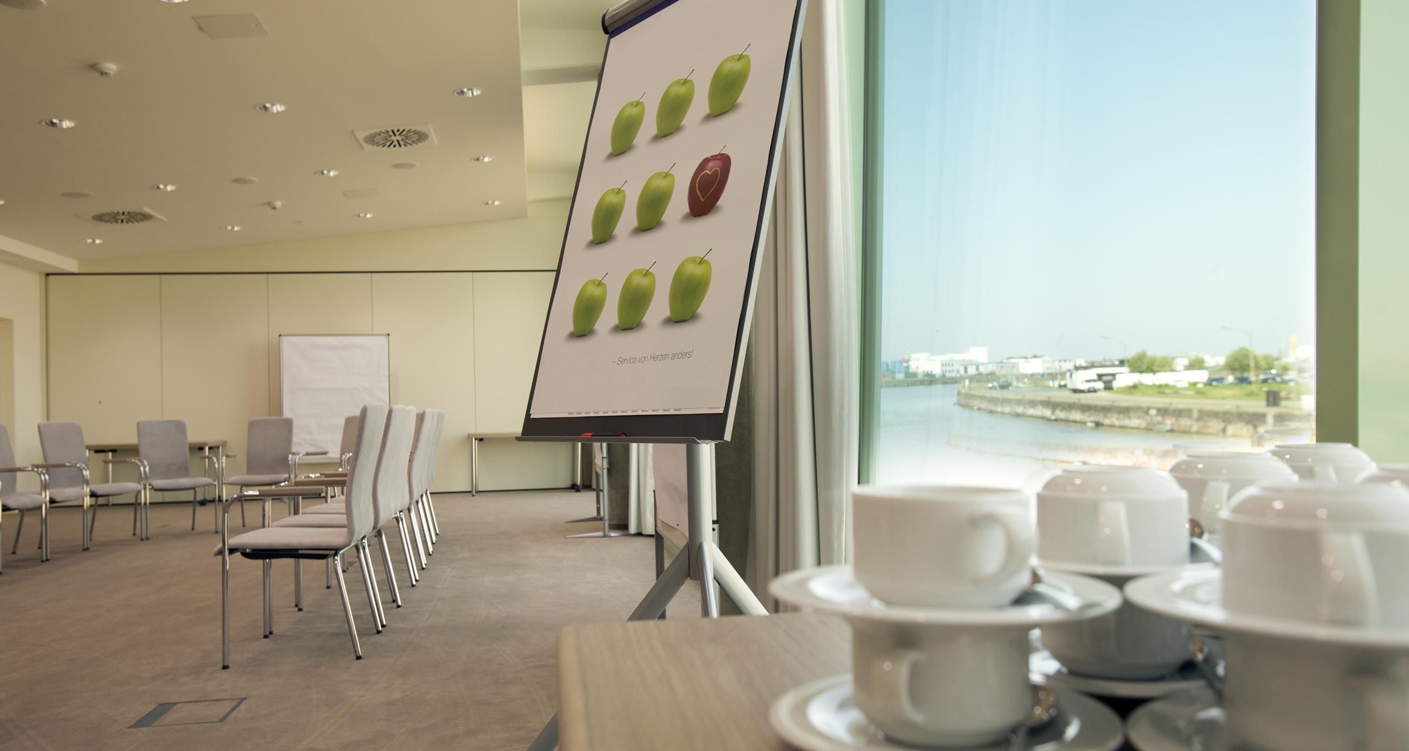 Uma sala de conferências com quadro branco, cadeiras e uma mesa com copos.