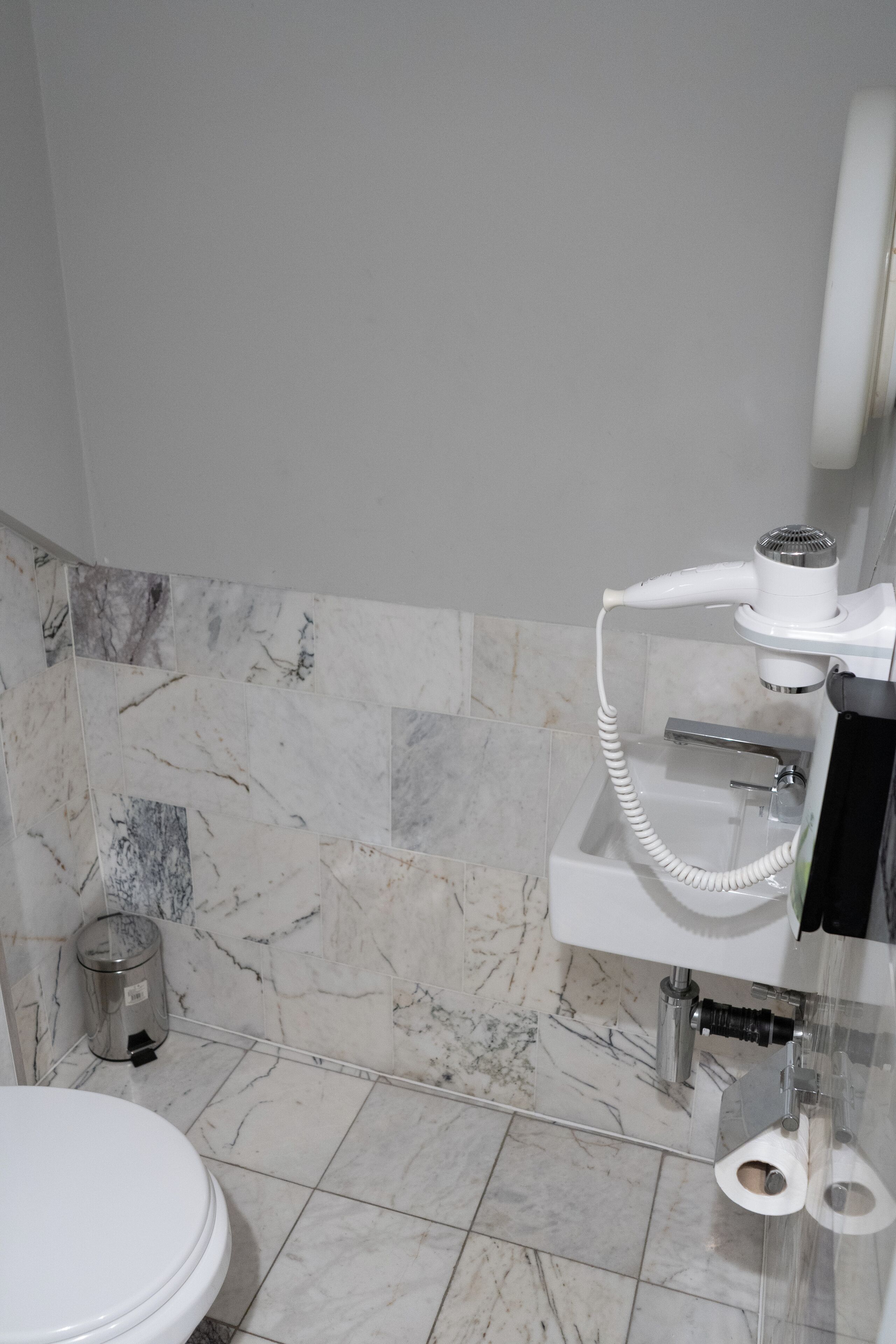 Casa de banho com sanita, lavatório e secador de cabelo.