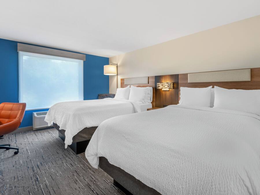 Quarto de hotel com duas camas, uma escrivaninha e uma cadeira.