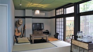 Um quarto tradicional em estilo japonês, com tatames, televisão, um violão e uma cama futon.
