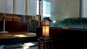 Um quarto com uma janela grande, um tradicional candeeiro japonês e um caminho de pedra.