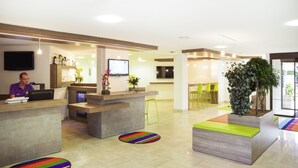 Uma área de recepção moderna com balcão, assentos e uma grande planta.
