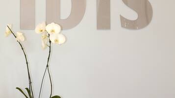Paredes com a palavra "ibis" em letras grandes, um vaso com uma orquídea e uma mesa de madeira.