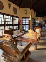 Quarto tradicional com móveis de madeira, janelas amplas e um abajur pendurado.