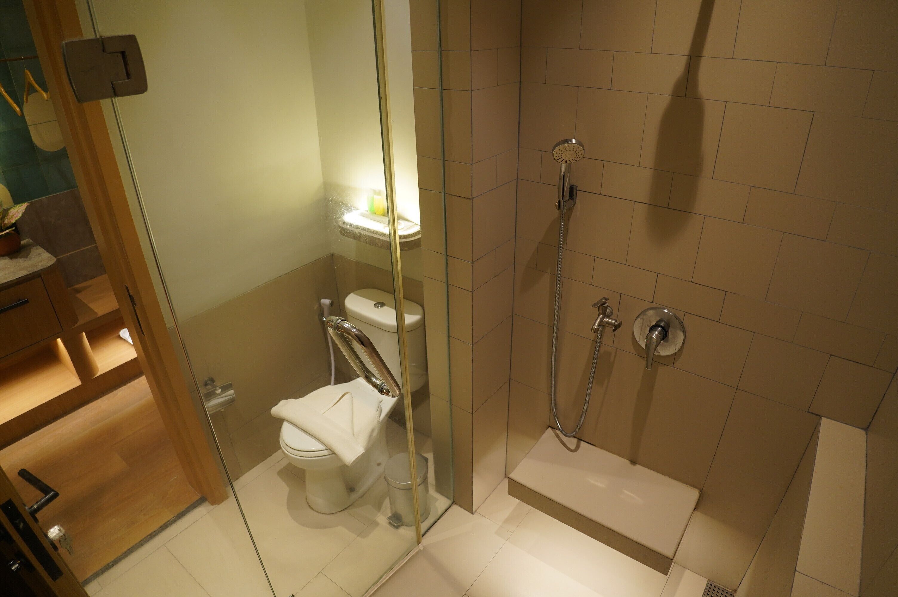 Uma casa de banho moderna com chuveiro separado por vidro, sanita e lavatório.