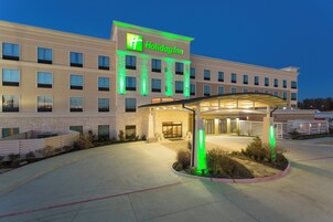 Um hotel Holiday Inn com entrada coberta e área ajardinada.