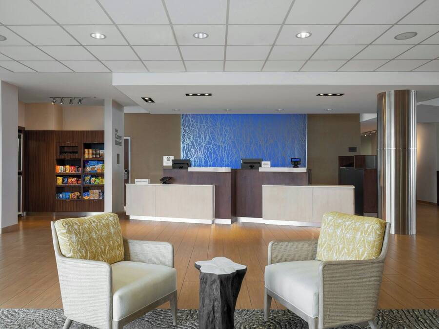 Um saguão de hotel com duas poltronas, um balcão de recepção e uma parede com padrão azul.