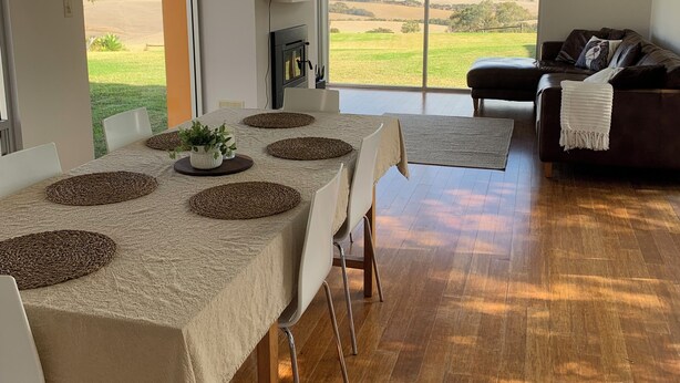 Uma sala de jantar espaçosa com uma mesa grande posta para seis pessoas, uma lareira e uma televisão na parede.