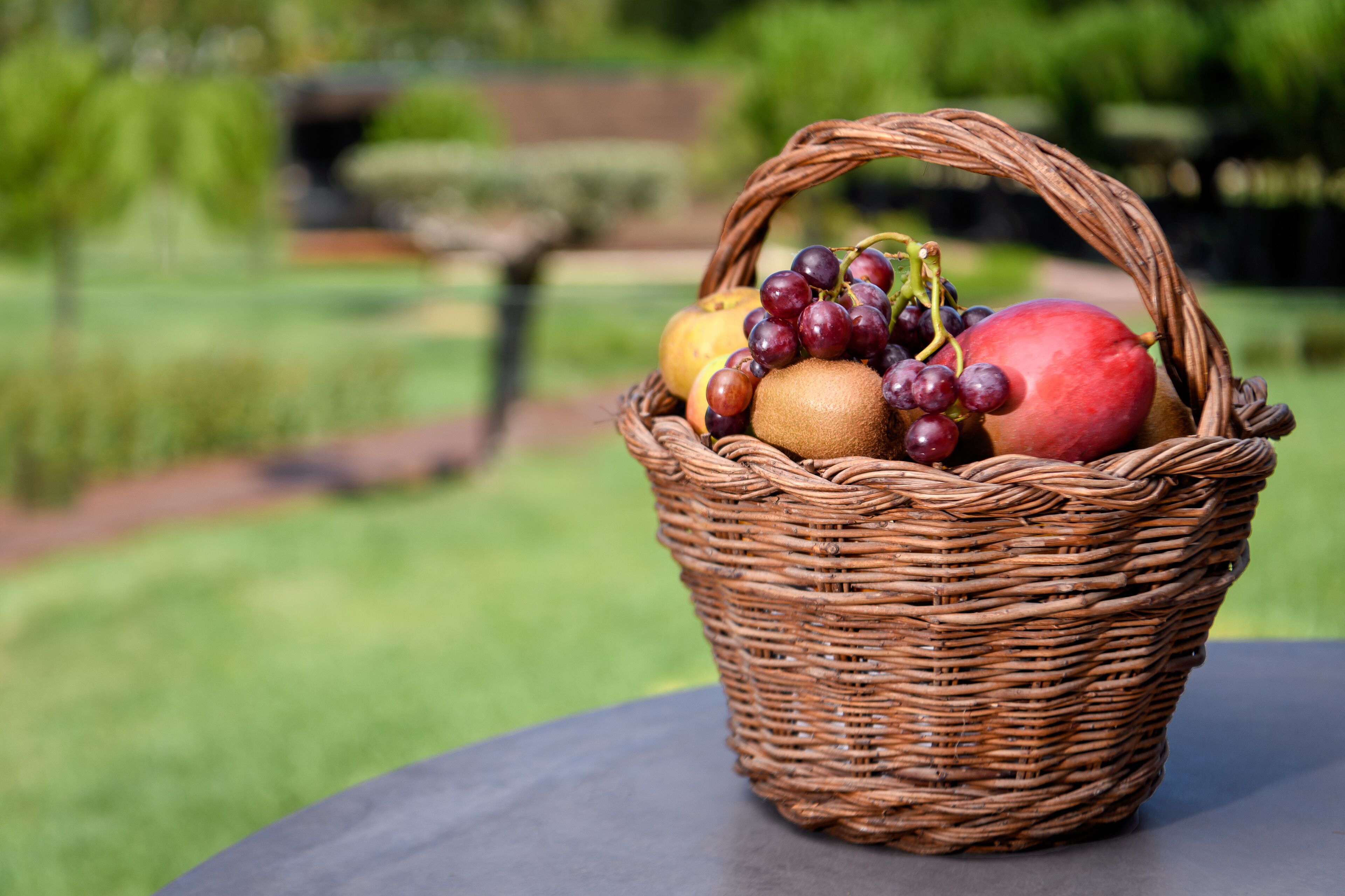 Uma cesta de vime com frutas sobre uma mesa.