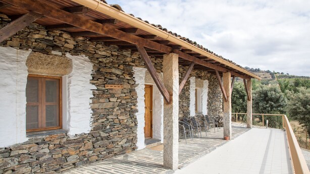 Um edifício de pedra com varanda de madeira e calçada de ladrilhos.