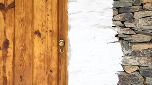 Uma porta de madeira, parede de pedra e gesso branco.