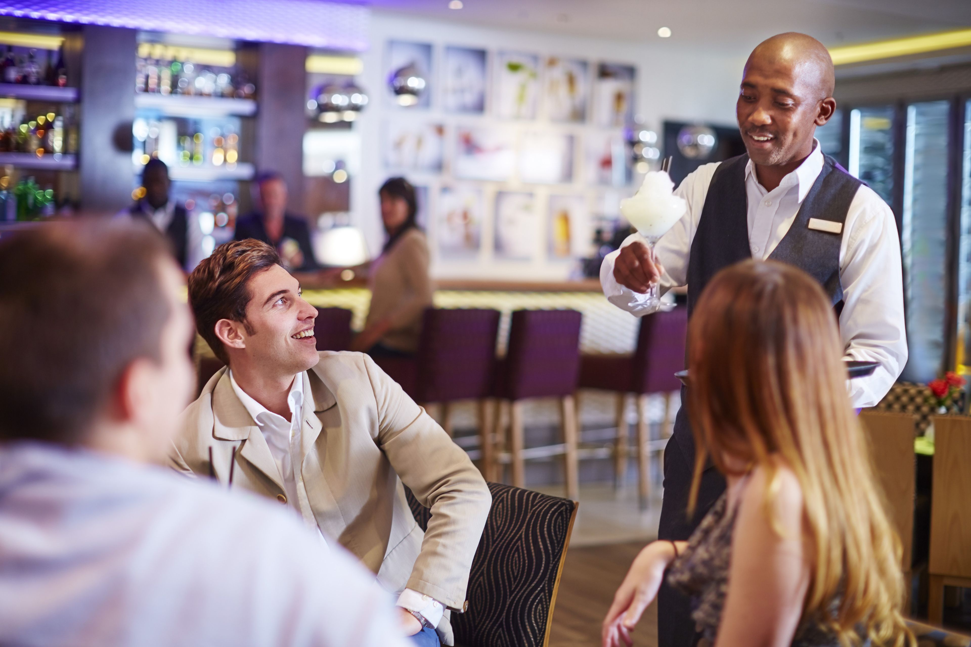 Uma área de bar com um barman servindo uma bebida a um cliente.