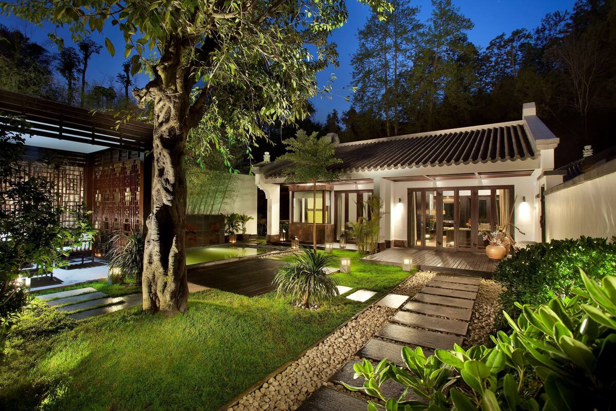Um edifício em estilo tradicional com telhado de telhas e um jardim bem cuidado com um caminho de pedra.