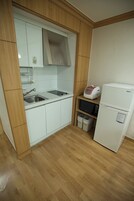 Cozinha compacta com pia, micro-ondas e geladeira.