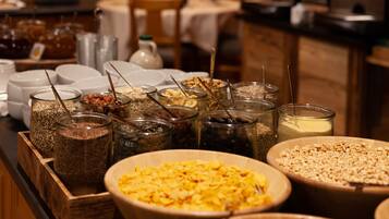 Buffet com diversos alimentos e recipientes, incluindo tigelas e potes de cereais e pastas.