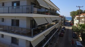 Um edifício com várias andares, varandas, vista para a rua e carros estacionados.