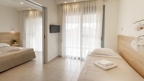 Um quarto moderno com uma cama grande, uma cama menor, uma TV e uma porta de vidro deslizante.