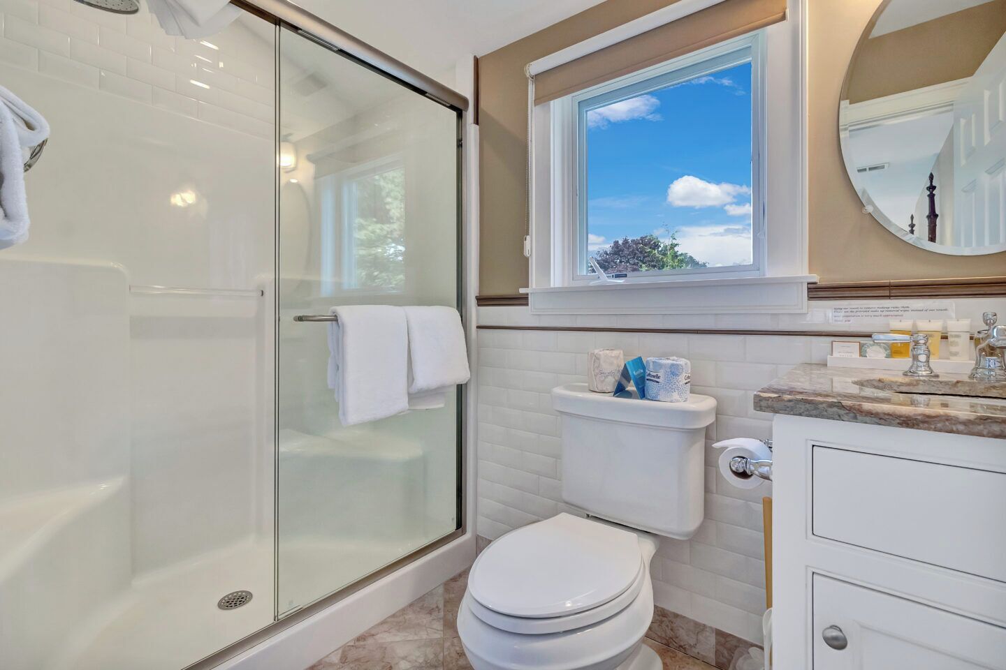 Uma casa de banho moderna com cabine de chuveiro em vidro, sanita e toucador com lavatório.
