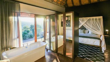 Casa de banho com banheira, chuveiro e uma grande janela com vista para o exterior.