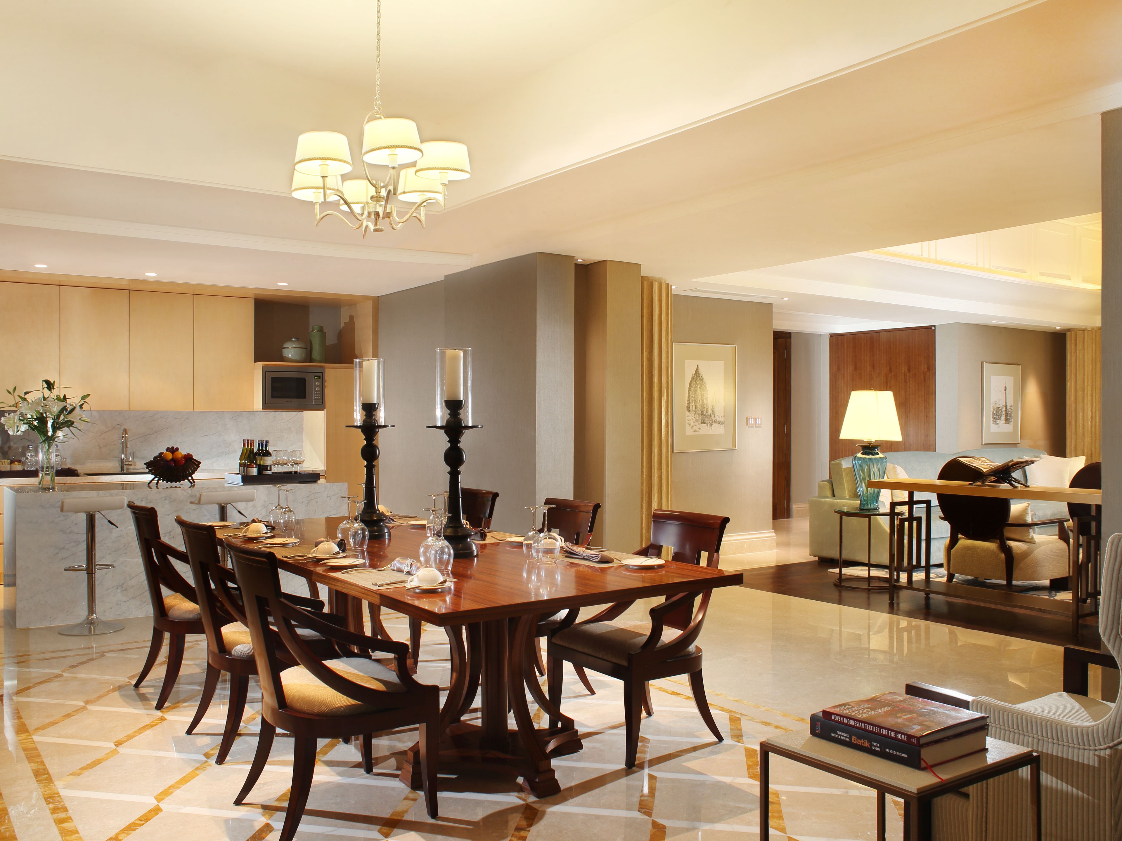 Uma sala de jantar ampla com uma grande mesa de madeira, várias cadeiras e um lustre.