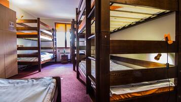Quarto com beliches, paredes de madeira e piso coberto por carpete.